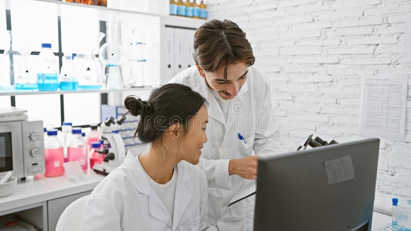 A Man and Woman in Lab Coats Analyze Data on a Computer in a Bright ...