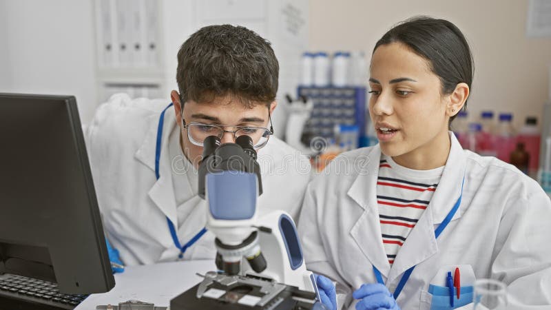 A Man and Woman in Lab Coats Analyze Samples Using a Microscope in a ...