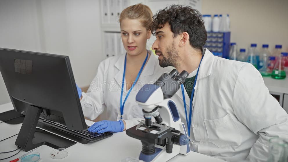A Man and Woman in Lab Coats Analyzing Data on a Computer in a Modern ...