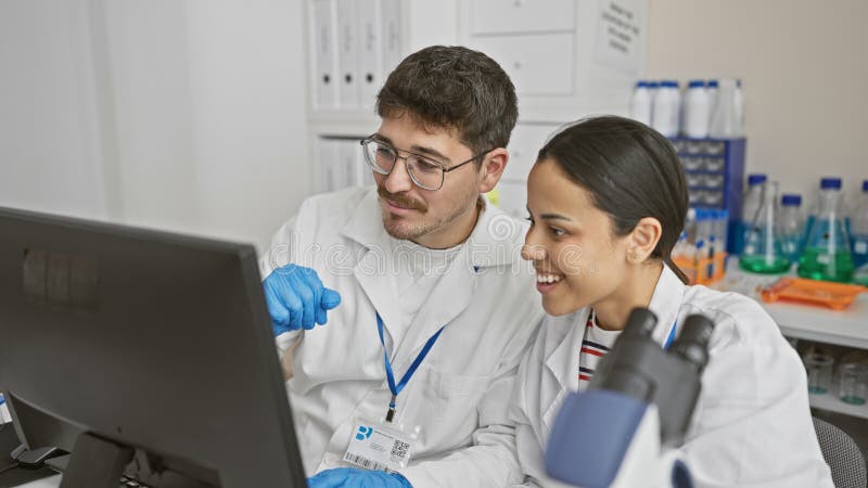 A Man and Woman in Lab Coats Collaborate As a Team in a Laboratory ...