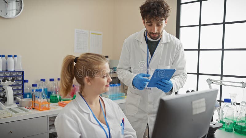 A Man and Woman in Lab Coats Work Together in a Laboratory, Using ...