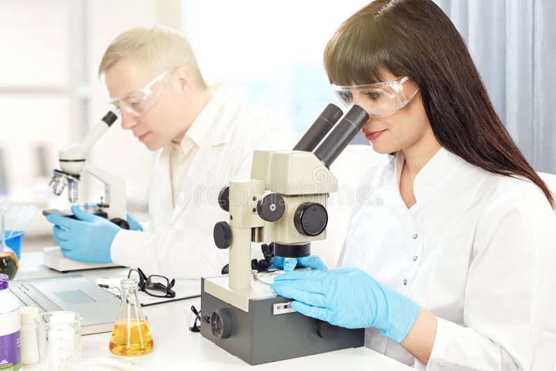 Man and a Woman, are Looking through a Microscope Stock Photo - Image ...