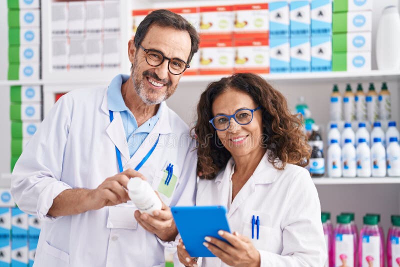 Man and Woman Pharmacists Using Touchpad Holding Pills Bottle at ...