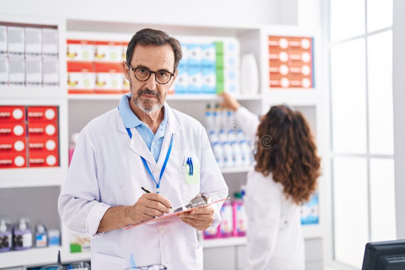 Man and Woman Pharmacists Writing on Document Working at Pharmacy Stock ...