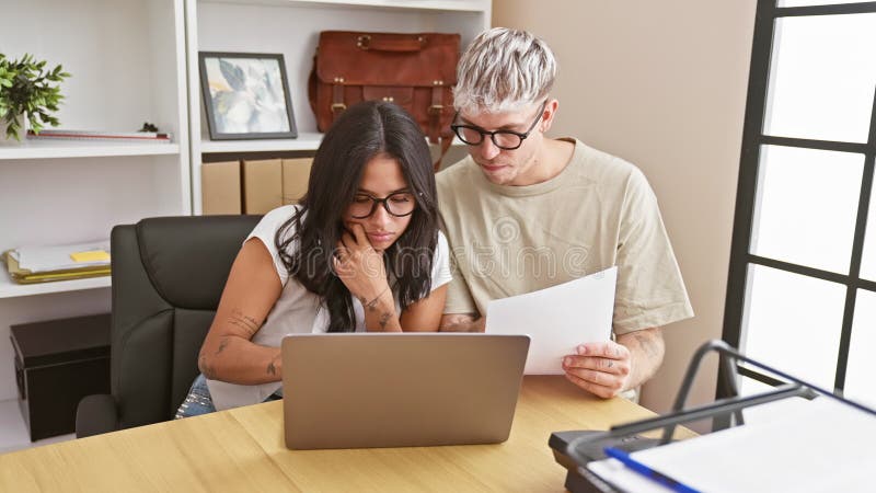 A Man and Woman Review Documents and Work on a Laptop in a Modern ...