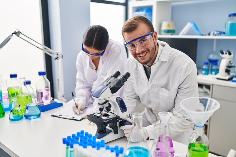 Man and Woman Scientist Partners Working Using Microscope and Writing ...