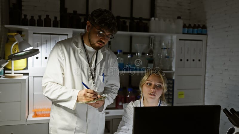 A Man and Woman, Scientists, Collaborate Using a Laptop and Taking ...