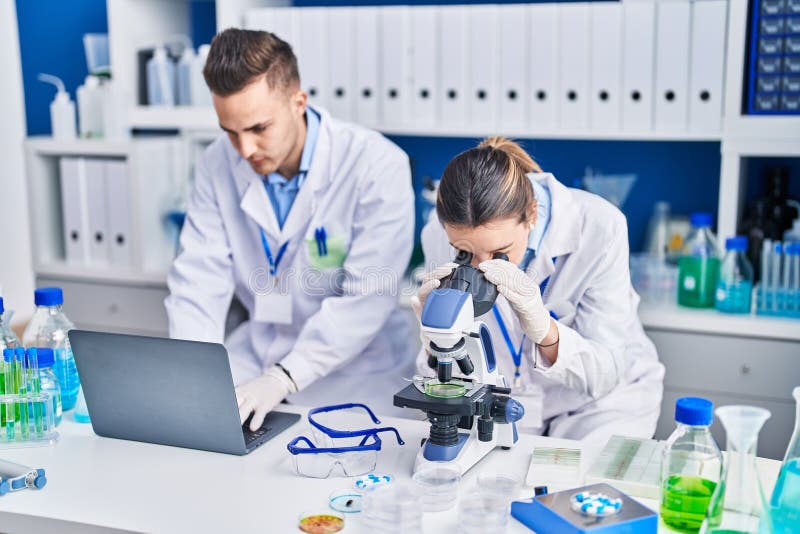Man and Woman Scientists Using Laptop and Microscope at Laboratory ...