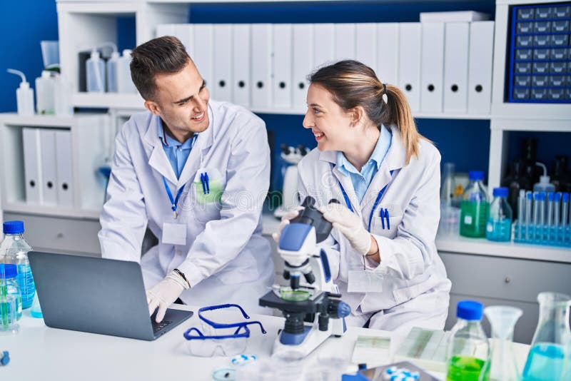 Man and Woman Scientists Using Laptop and Microscope at Laboratory ...