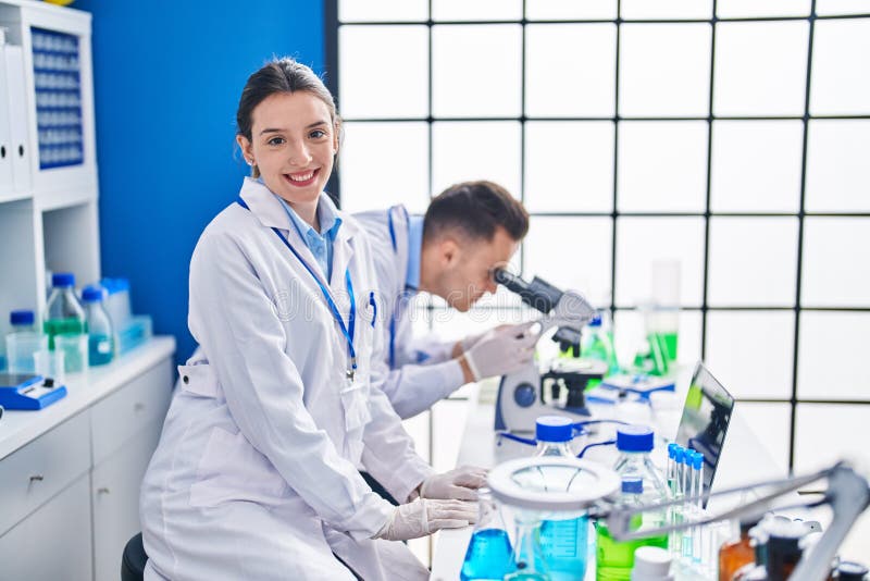 Man and Woman Scientists Using Laptop and Microscope at Laboratory ...