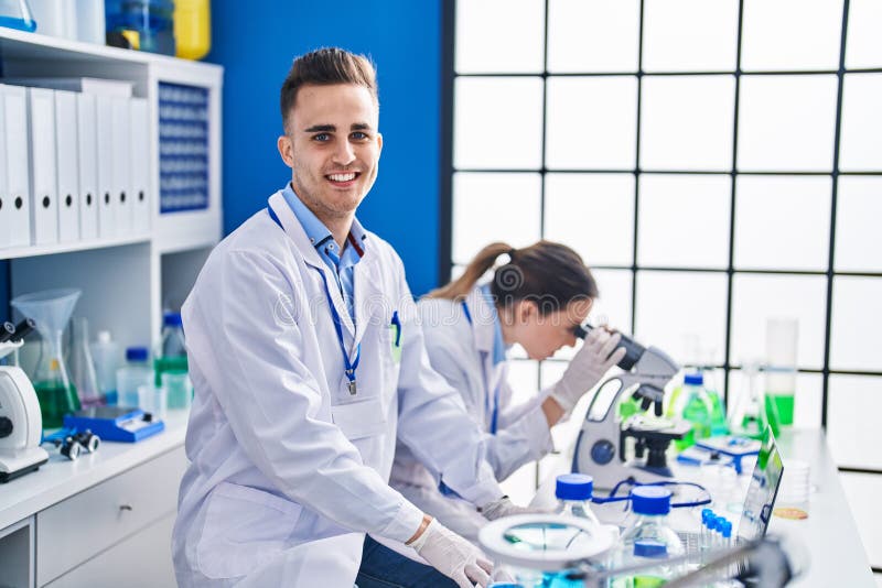 Man and Woman Scientists Using Laptop and Microscope at Laboratory ...