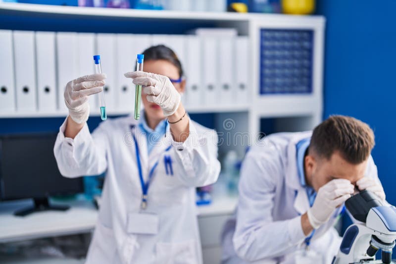 Man and Woman Scientists Using Microscope Holding Test Tubes at ...