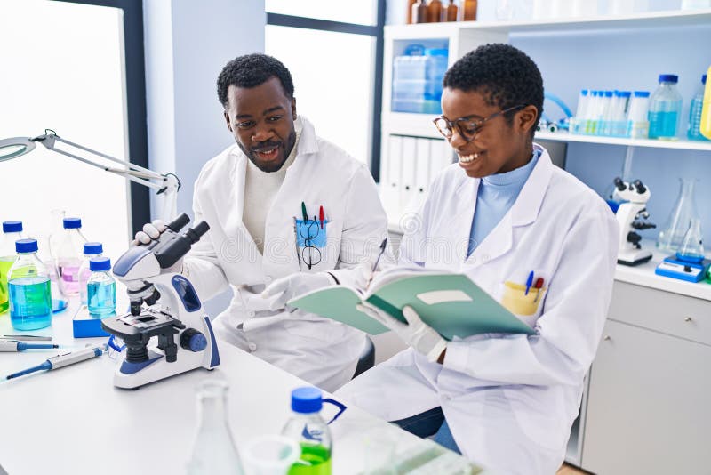 Man and Woman Scientists Using Microscope Writing on Notebook at ...