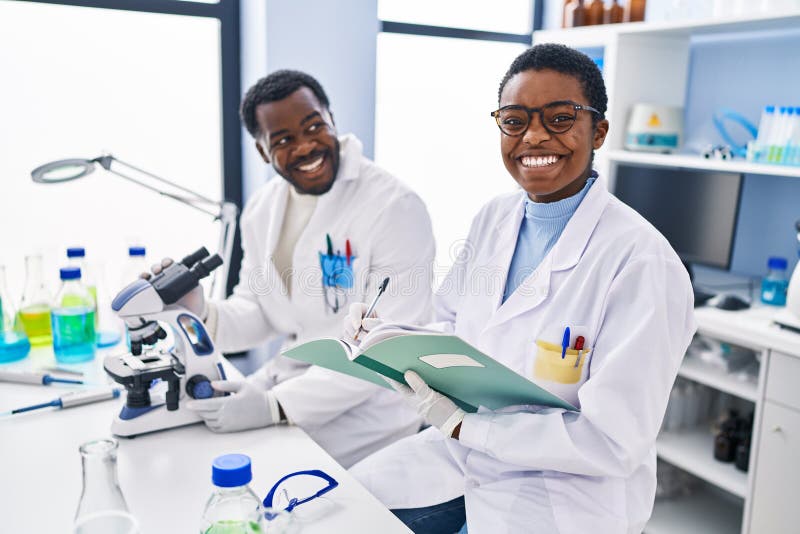 Man and Woman Scientists Using Microscope Writing on Notebook at ...