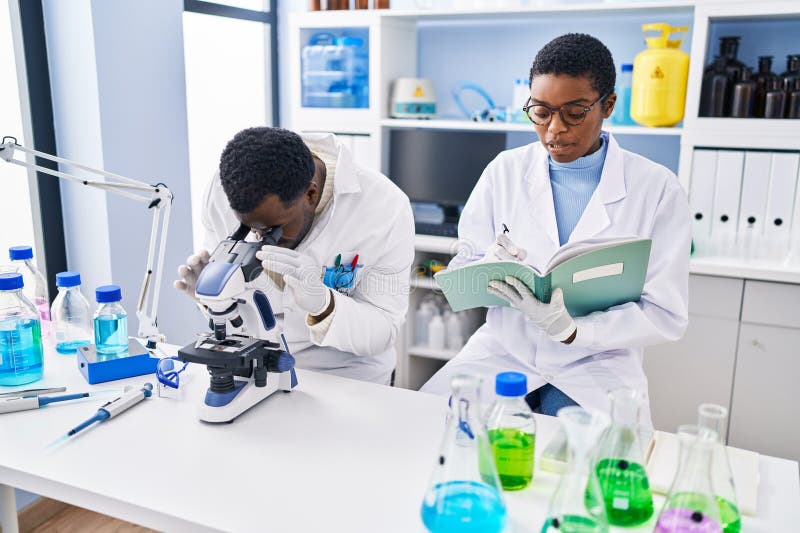 Man and Woman Scientists Using Microscope Writing on Notebook at ...