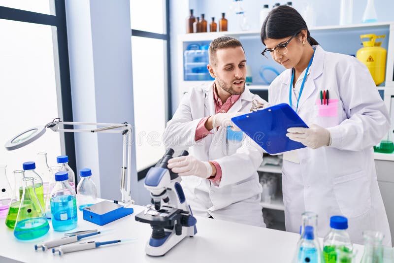 Man and Woman Wearing Scientists Uniform Using Microscope at Laboratory ...