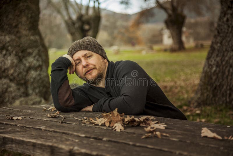 Man with Wool Hat Sitting on the Bench in the Park in Autumn Background ...