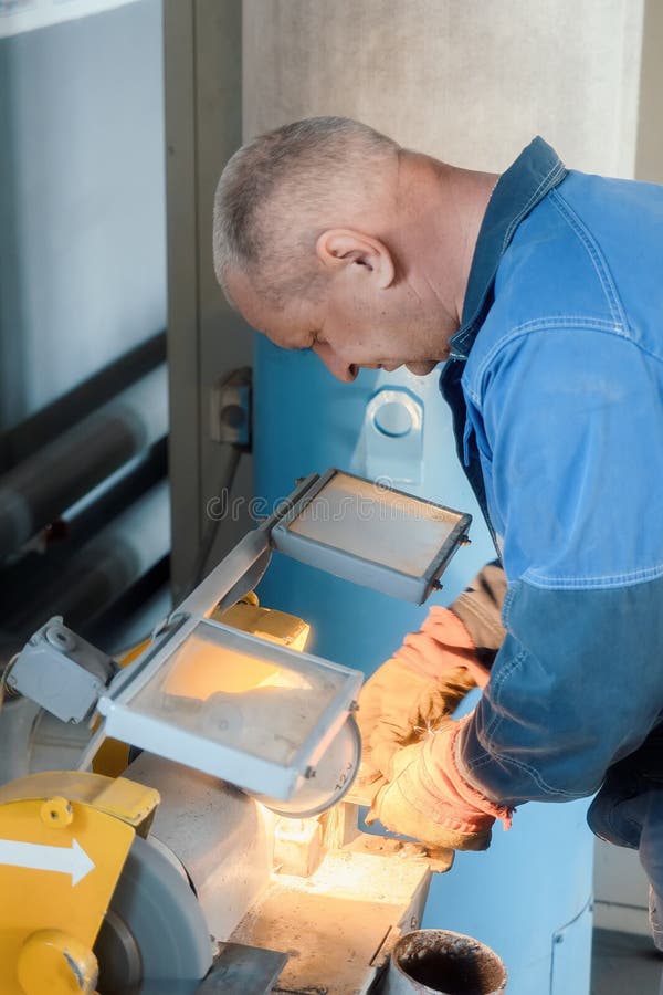 Man in Work Clothes Sharpens Chisel at Grinder. Worker in Turning Shop ...