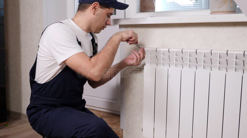 Man in Work Overalls Using Wrench while Installing Heating Radiator in ...