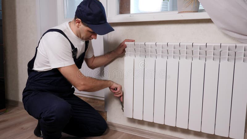 Man in Work Overalls Using Wrench while Installing Heating Radiator in ...