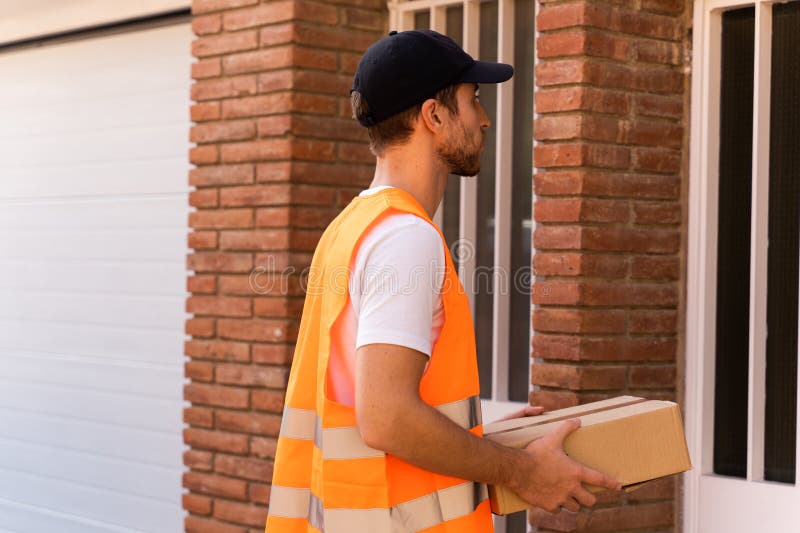 A Man Working As a Package Deliveryman in an Orange Uniform Delivers a ...