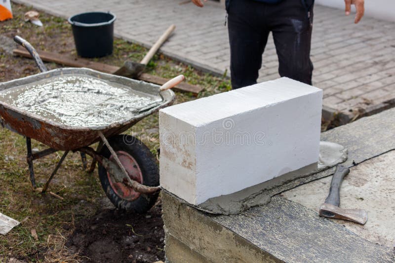 A Man is Working on a Brick Wall with a Wheelbarrow and a Hammer Stock ...