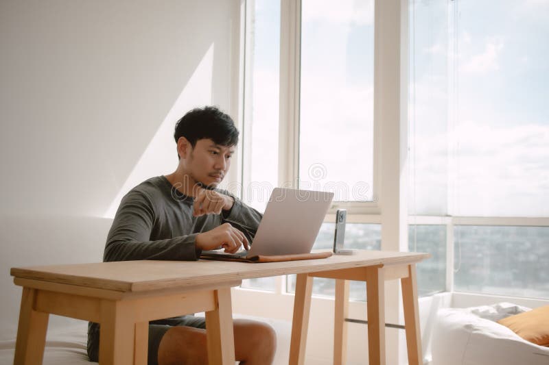 Man Working with Computer in Apartment with City View at the Windows in ...