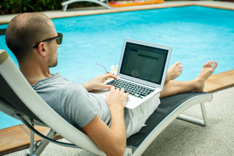 A Man Working at the Computer Next To the Pool Stock Photo - Image of ...