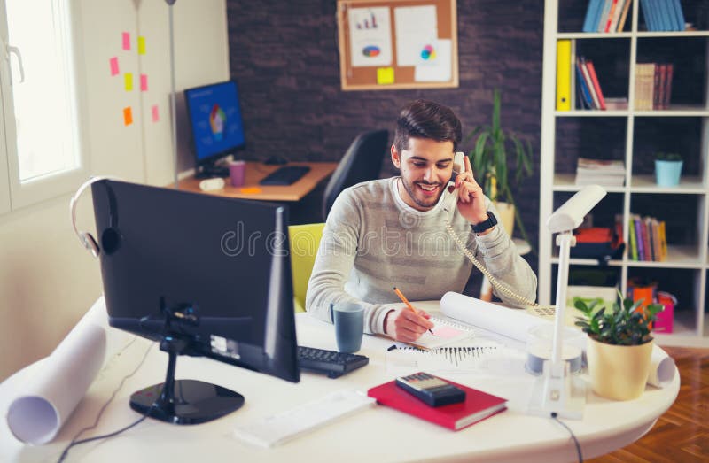 Man Working on Computer Talking on Landline Phone Stock Image - Image ...