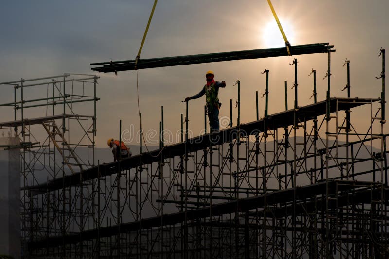 Man Working on Construction Site with Scaffold and Building with Sunset ...