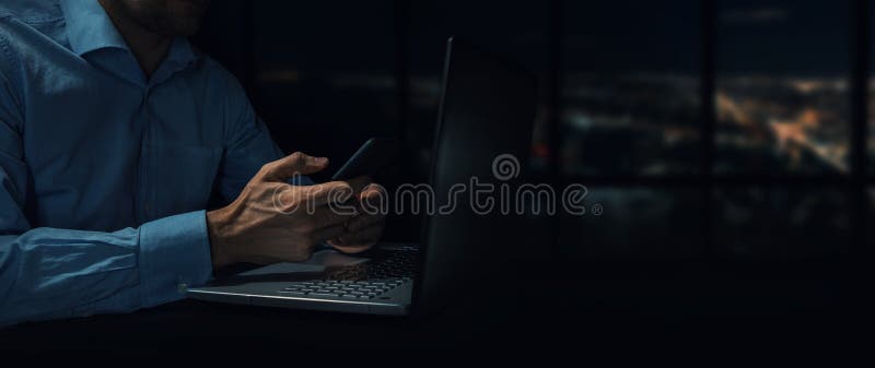 Man Working in Dark Office at Night. Using Mobile Phone and Laptop ...