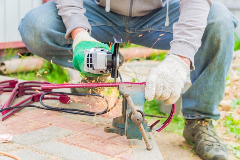 Man Working with Electric Grinder Tool on a Steel Structure Outdoors ...