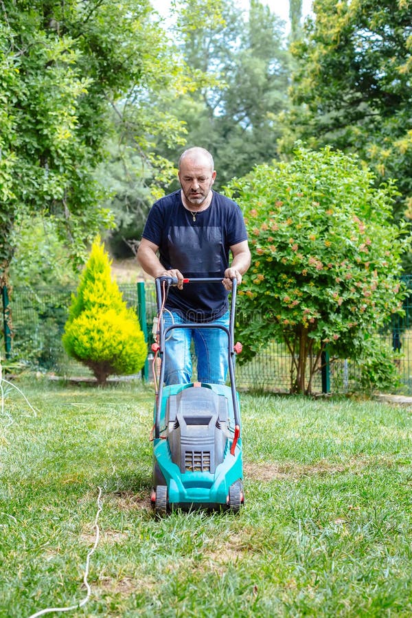 Man Working in Garden Cutting Grass with Lawn Mower Stock Image - Image ...