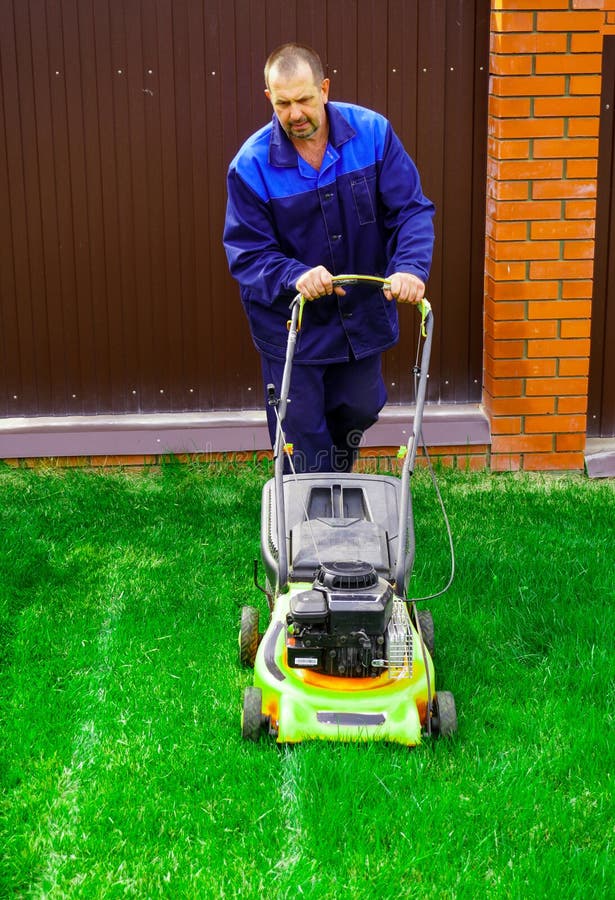 The Man is Working in the Garden. Mowing Grass with a Lawn Mower Stock ...
