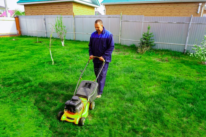 The Man is Working in the Garden. Mowing Grass with a Lawn Mower Stock ...