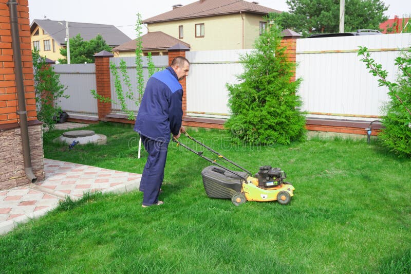The Man is Working in the Garden. Mowing Grass with a Lawn Mower Stock ...