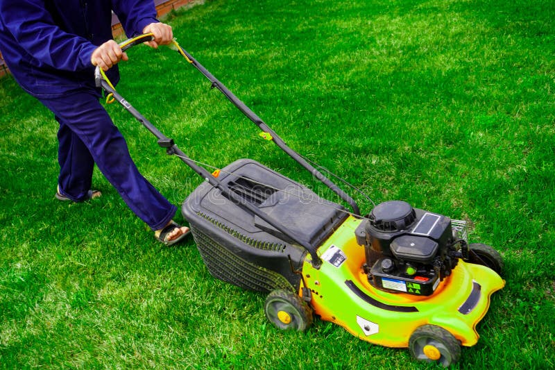 The Man is Working in the Garden. Mowing Grass with a Lawn Mower Stock ...