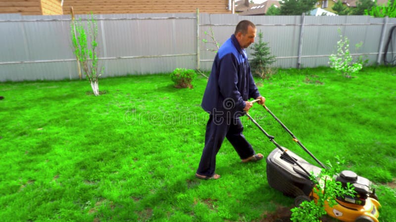 The Man is Working in the Garden. Mowing Grass with a Lawn Mower Stock ...