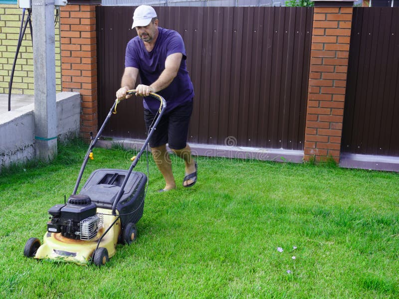 The Man is Working in the Garden. Mowing Grass with a Lawn Mower Stock ...
