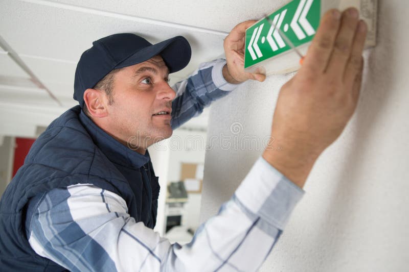 Man Working on Illuminated Exit Sign To Wall Stock Photo - Image of ...