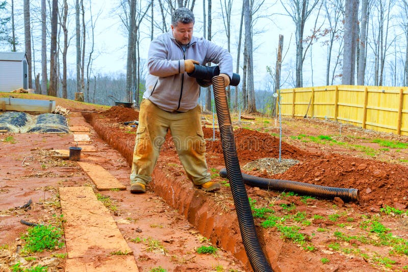 Man Constructs Drainage System in Backyard during Overcast Day with ...