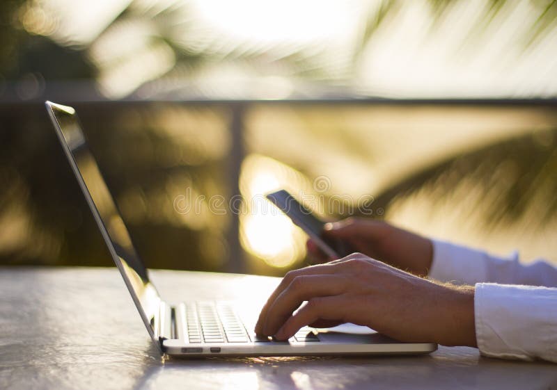 A Man Working with a Laptop and Cell Phone at Sunset Stock Photo ...