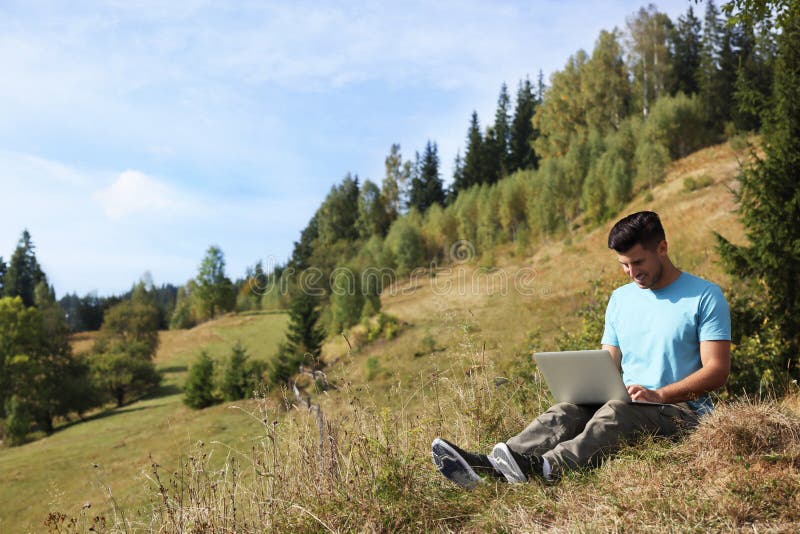 Man Working with Laptop Outdoors Surrounded by Beautiful Nature. Space ...