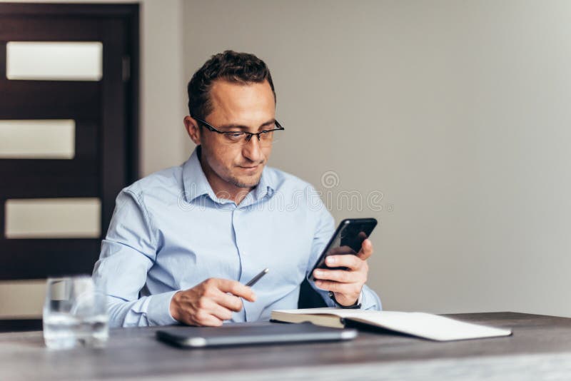Man Working in the Office and Use Smartphone, Documents on His Desk ...