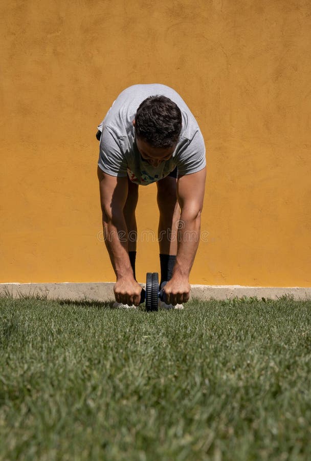 Man Working Out with Double Wheel Ab Rollers Outdoors Below Harsh ...