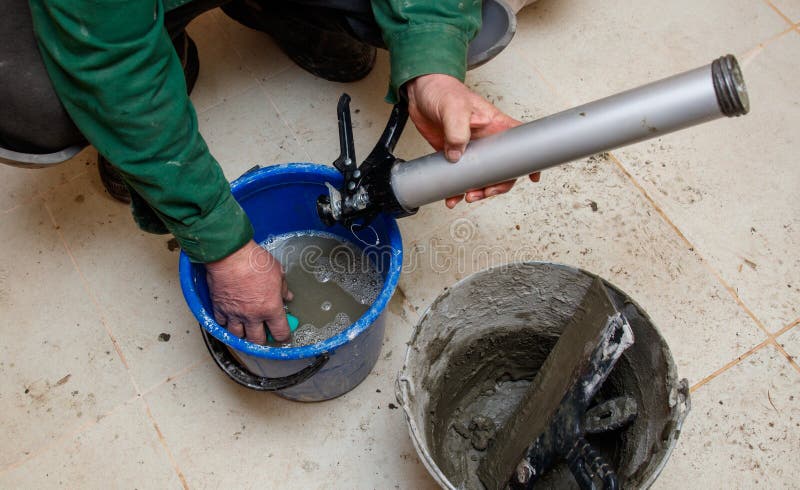 A Man is Working on a Project, Using a Blue Bucket and a Tube Stock ...