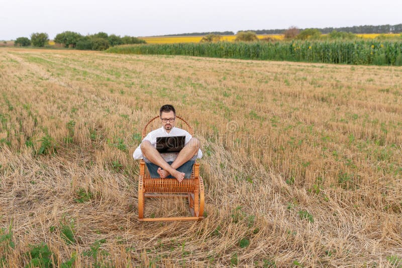 Man Working Remotely Outdoors with Notebook on Beveled Field. Using ...