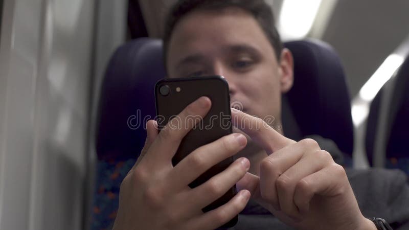 Young Man Working on a Train and Having Fun with a Smartphone and ...