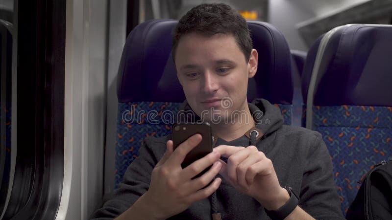 Young Man Working on a Train and Having Fun with a Smartphone and ...