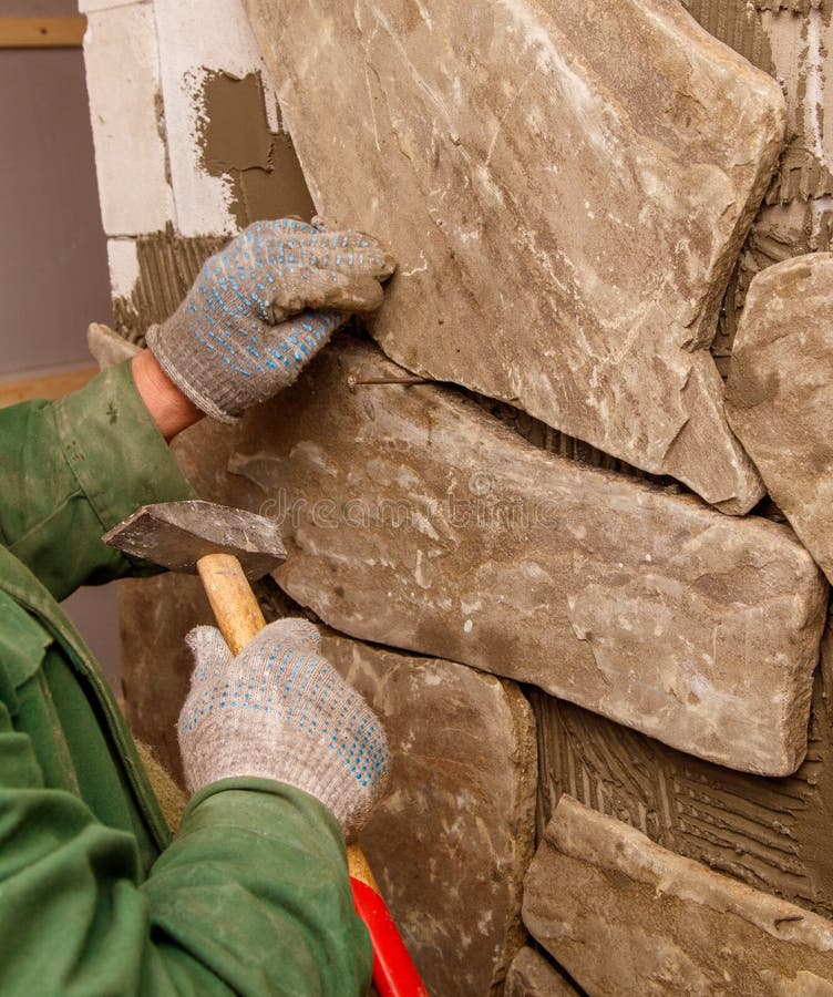 A Man is Working on a Wall, Using a Hammer and Chisel To Shape a Stone ...